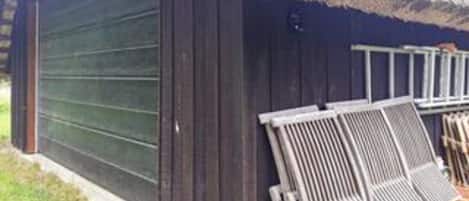 Um edifício com fachada escura, porta de metal e cerca metálica.
