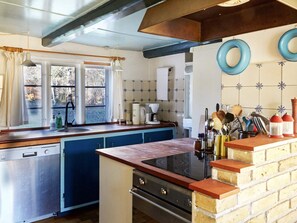 Cozinha equipada com máquina de lavar louça embutida, fogão e parede decorada com tijolos.