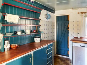 Cozinha com armários azuis, bancada de madeira e porta azul.
