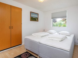 Quarto com cama de casal, guarda-roupa, pintura e janela vista para o verde.