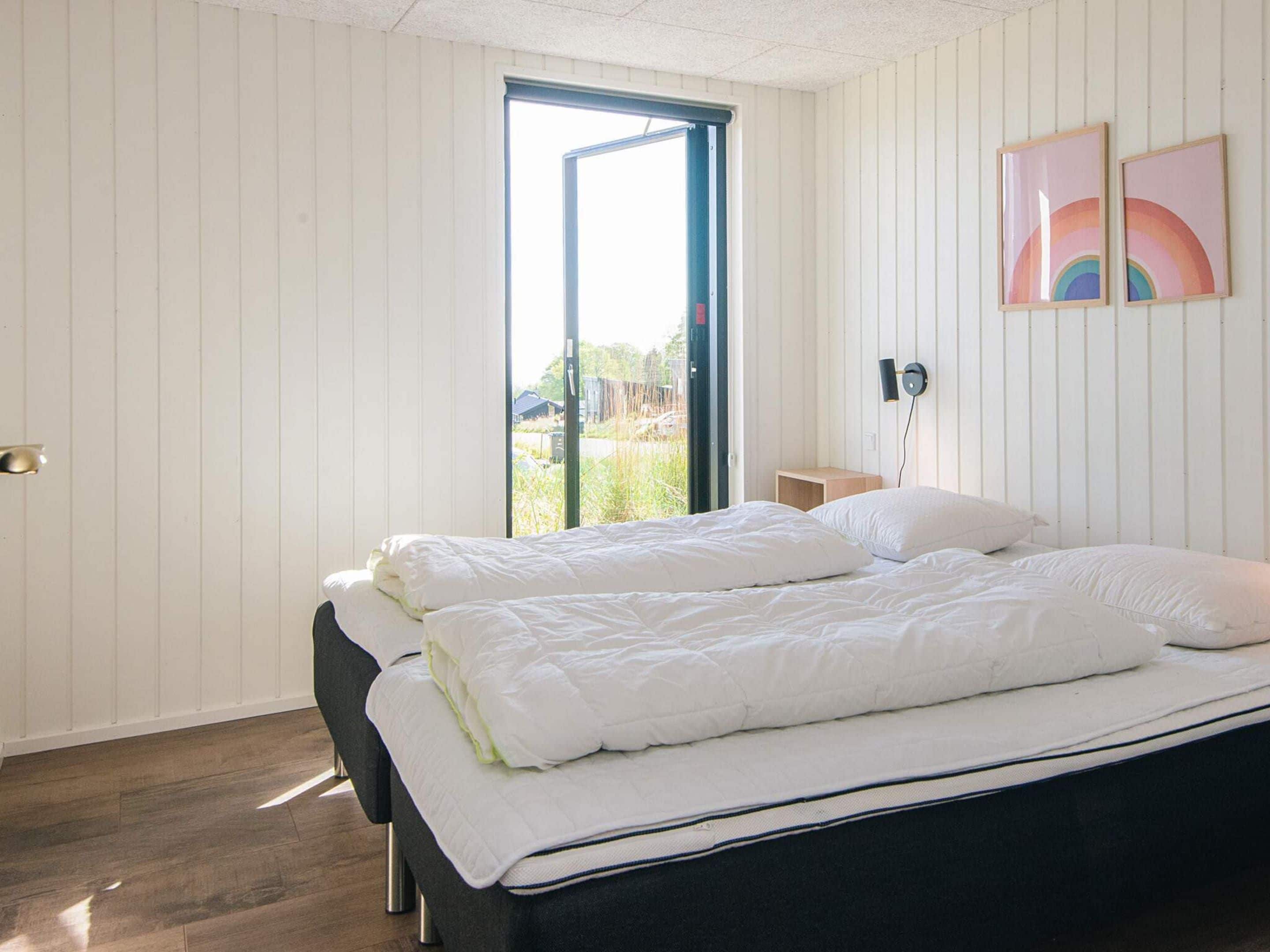 Quarto com cama, janela e luminária fixada na parede.