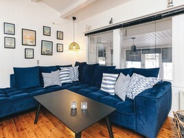 Uma sala de estar moderna com um sofá seccional azul, uma mesa de centro escura e obras de arte emolduradas nas paredes.