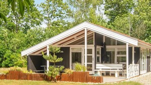 Uma casa moderna com varanda coberta, deck de madeira e pequeno jardim.
