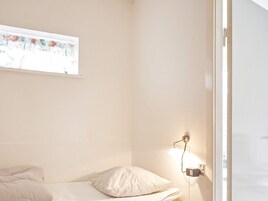 Quarto com cama, luminária na parede e janela com vista.