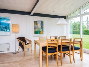Uma área de refeições com mesa e cadeiras de madeira, luminária pendente e obras de arte nas paredes.