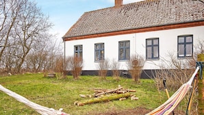 Uma casa branca com telhado de cerâmica, cercada por um gramado e árvores sem folhas.