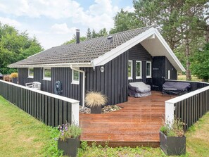 Uma cabana com deck de madeira, área de estar coberta ao ar livre e exterior preto.