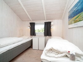 Acomodação compacta, com um quarto, duas camas, cozinha compacta e janela com cortinas.