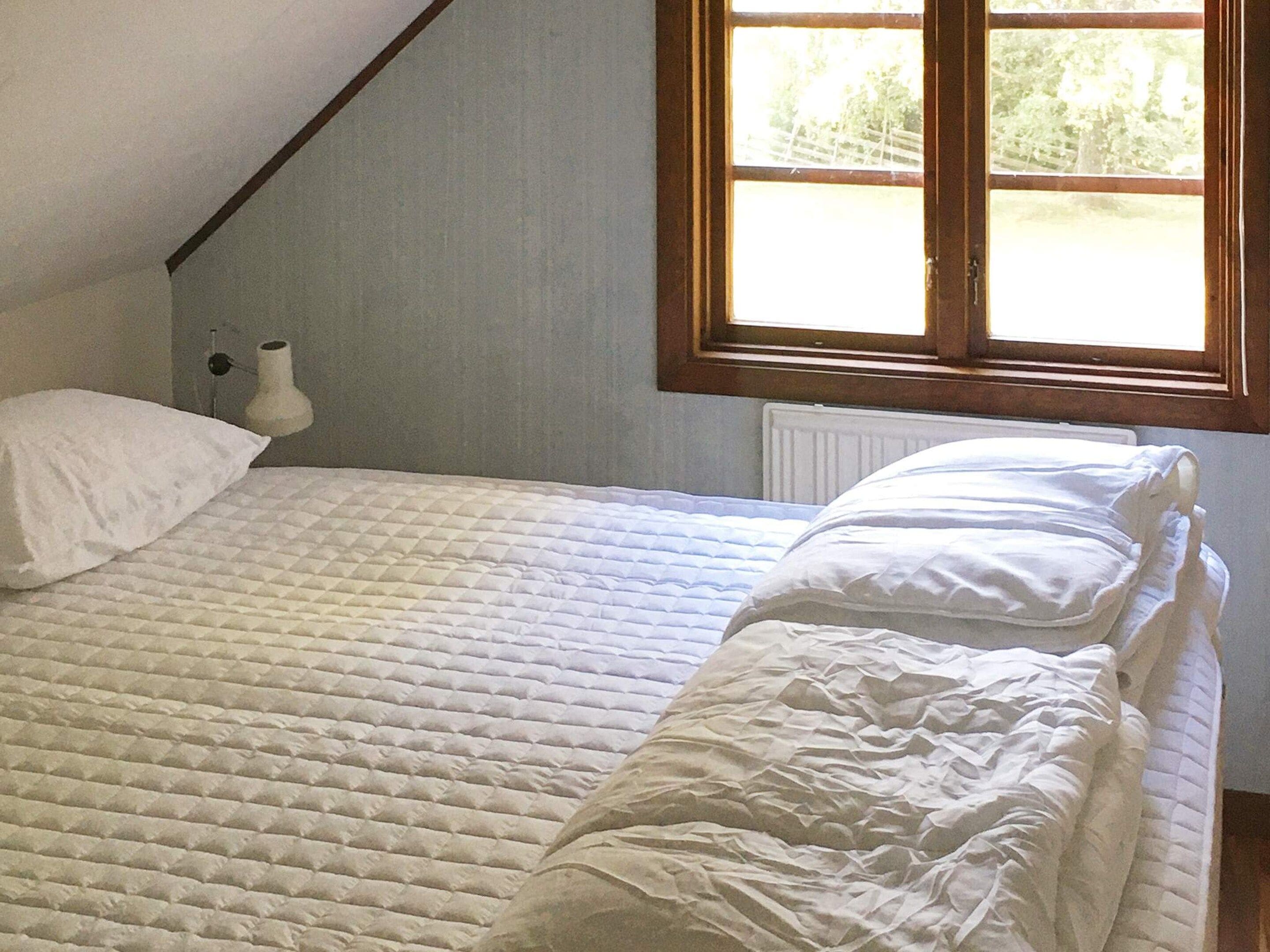 Quarto com cama, janela e radiador.