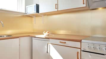 Uma cozinha moderna com armários brancos, uma pia de aço inoxidável, um micro-ondas e um forno Zanussi.