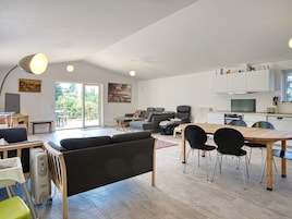 Uma sala ampla com sofá, mesa de jantar, cadeiras e cozinha.