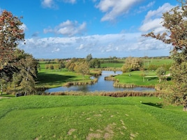 Um campo de golfe com lago, árvores e céu claro.
