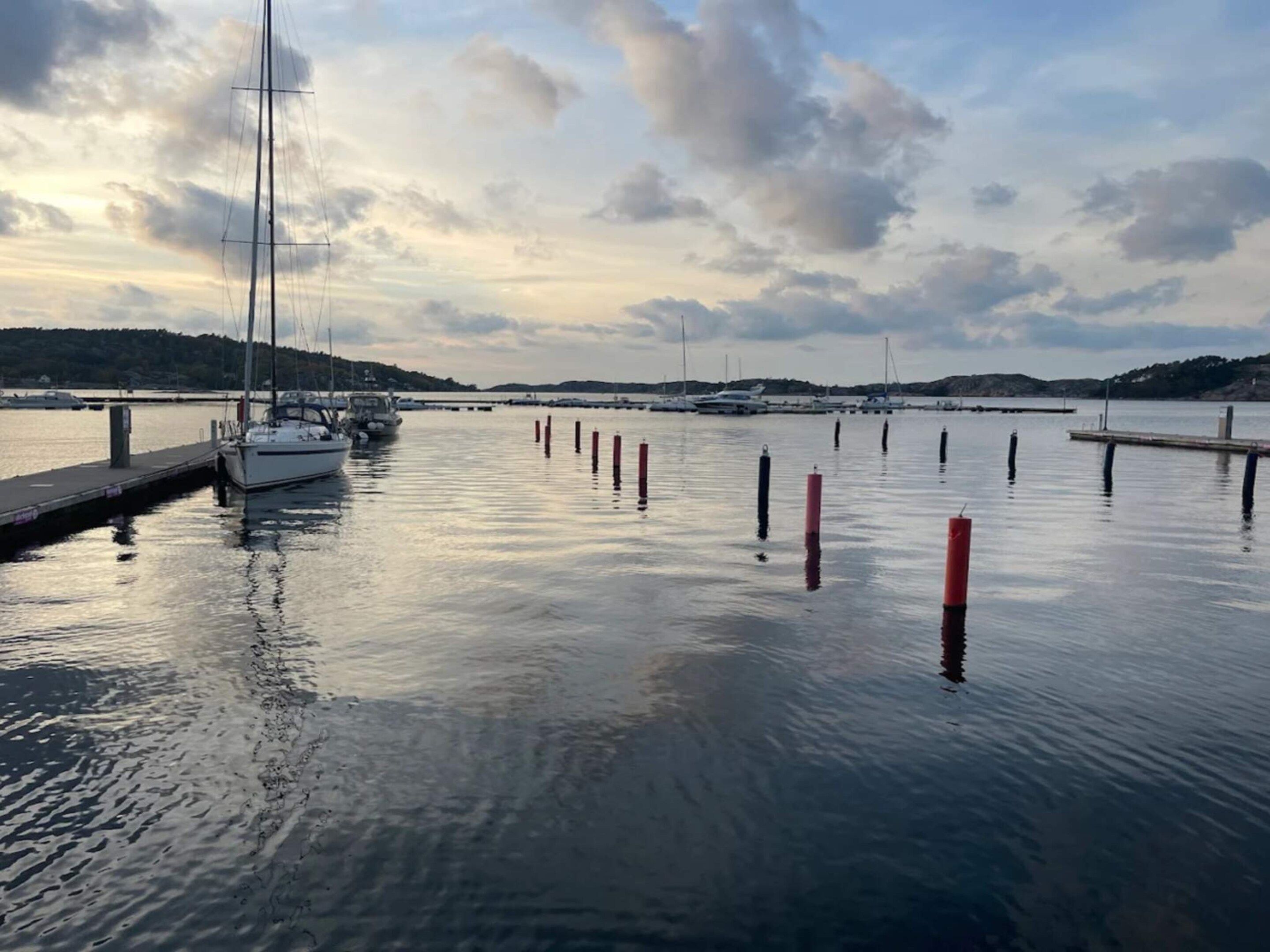 Marina com barcos atracados, água calma e céu nublado.