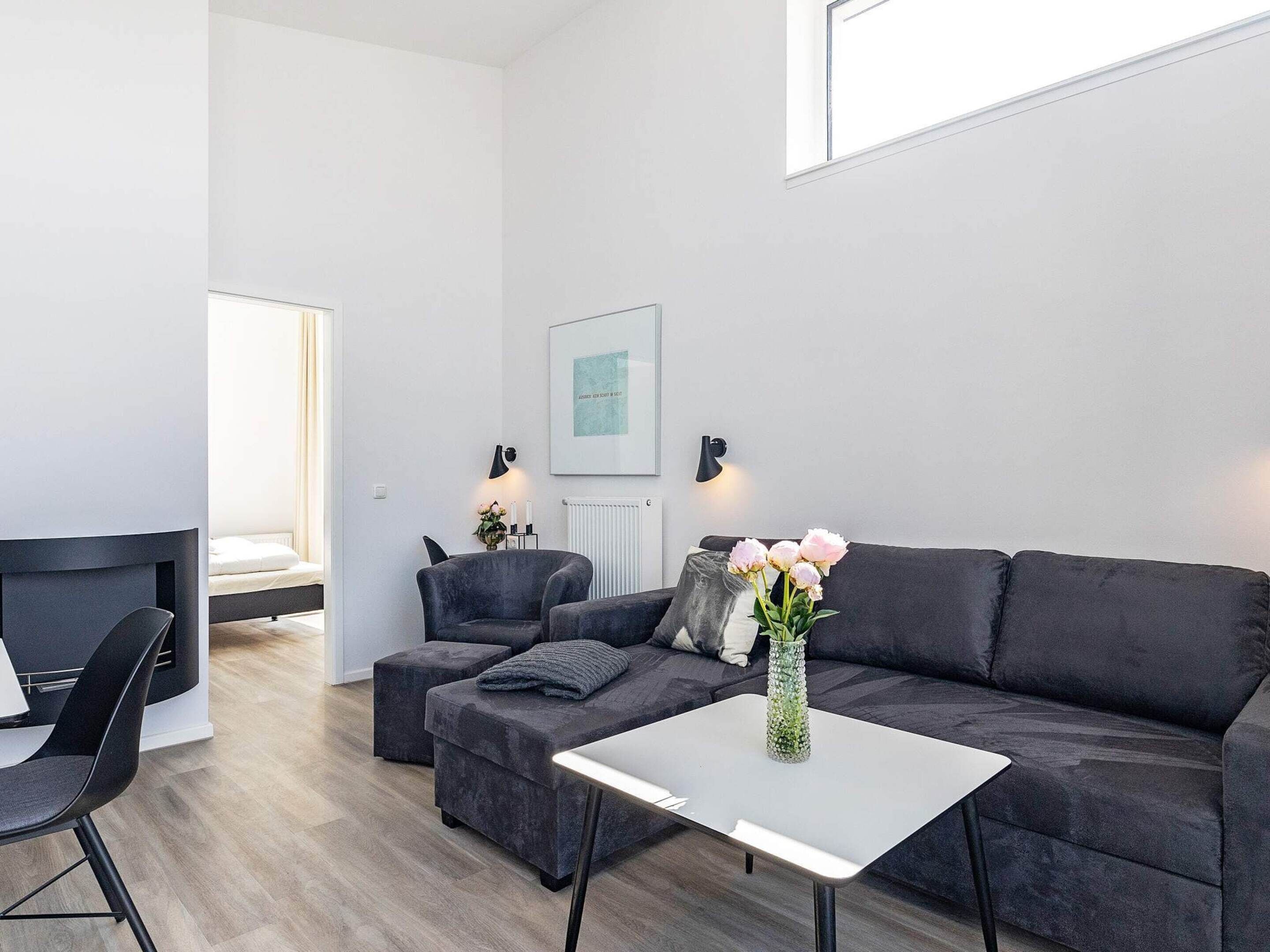 Uma sala de estar moderna com sofá, duas poltronas, mesa de centro e lareira.