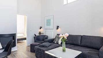 Uma sala de estar moderna com sofá, duas poltronas, mesa de centro e lareira.