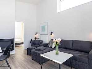 Uma sala de estar moderna com sofá, duas poltronas, mesa de centro e lareira.