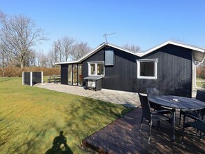 Uma casa moderna com um espaço de varanda, uma mesa e cadeiras.