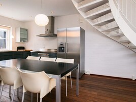 Cozinha moderna com ilha central, eletrodomésticos de aço inoxidável e escada em espiral.