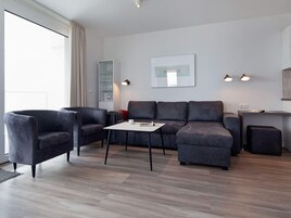Uma sala de estar moderna com um conjunto de sofás, uma mesa de centro e uma escrivaninha com duas luminárias.
