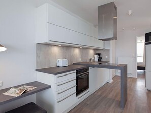 Cozinha moderna com forno embutido, cafeteira e torradeira na bancada.