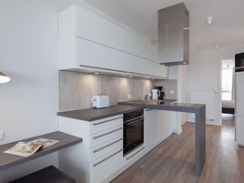 Cozinha moderna com forno embutido, cafeteira e torradeira na bancada.