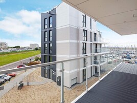 Um edifício moderno com varanda com vista para um porto de iates.