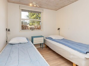 Quarto com duas camas de solteiro, janela com vista, pequena escrivaninha e luminária de teto.