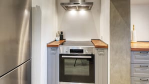 Cozinha compacta com geladeira de aço inoxidável, forno Bosch e coifa moderna.