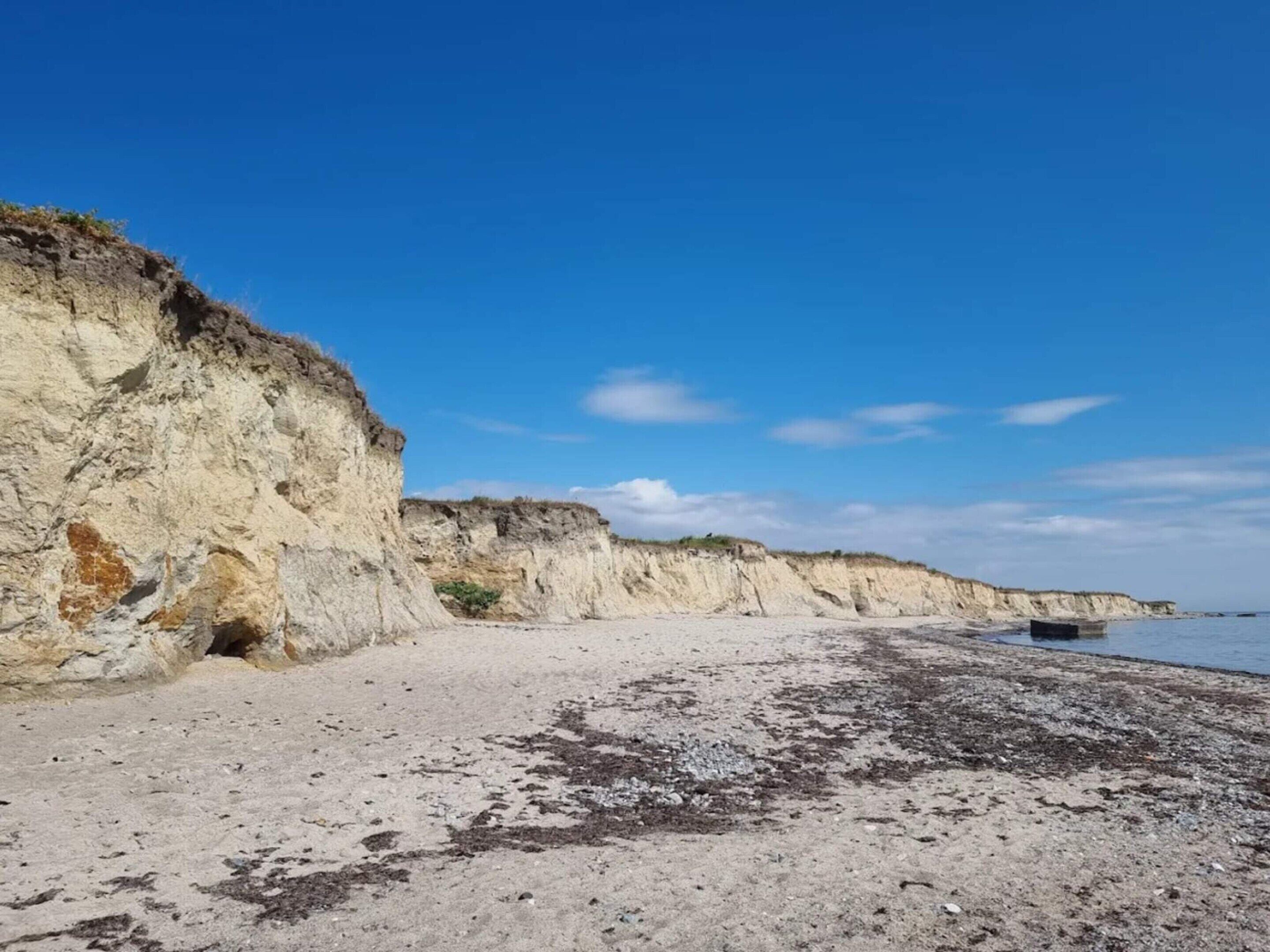 Uma praia costeira com falésias brancas e areal arenoso.