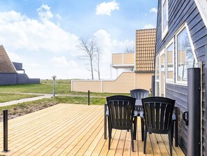 Um deck com piso de madeira e duas cadeiras pretas.