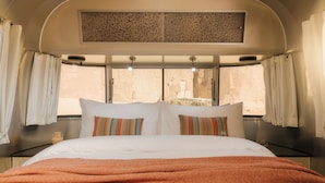 Quarto com cama, duas janelas, cortinas e cabeceira.