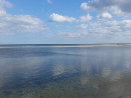 Uma praia com águas cristalinas e uma faixa de areia sob um céu parcialmente nublado.
