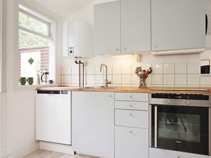Cozinha moderna com armários brancos, máquina de lavar louça, pia e forno Siemens.