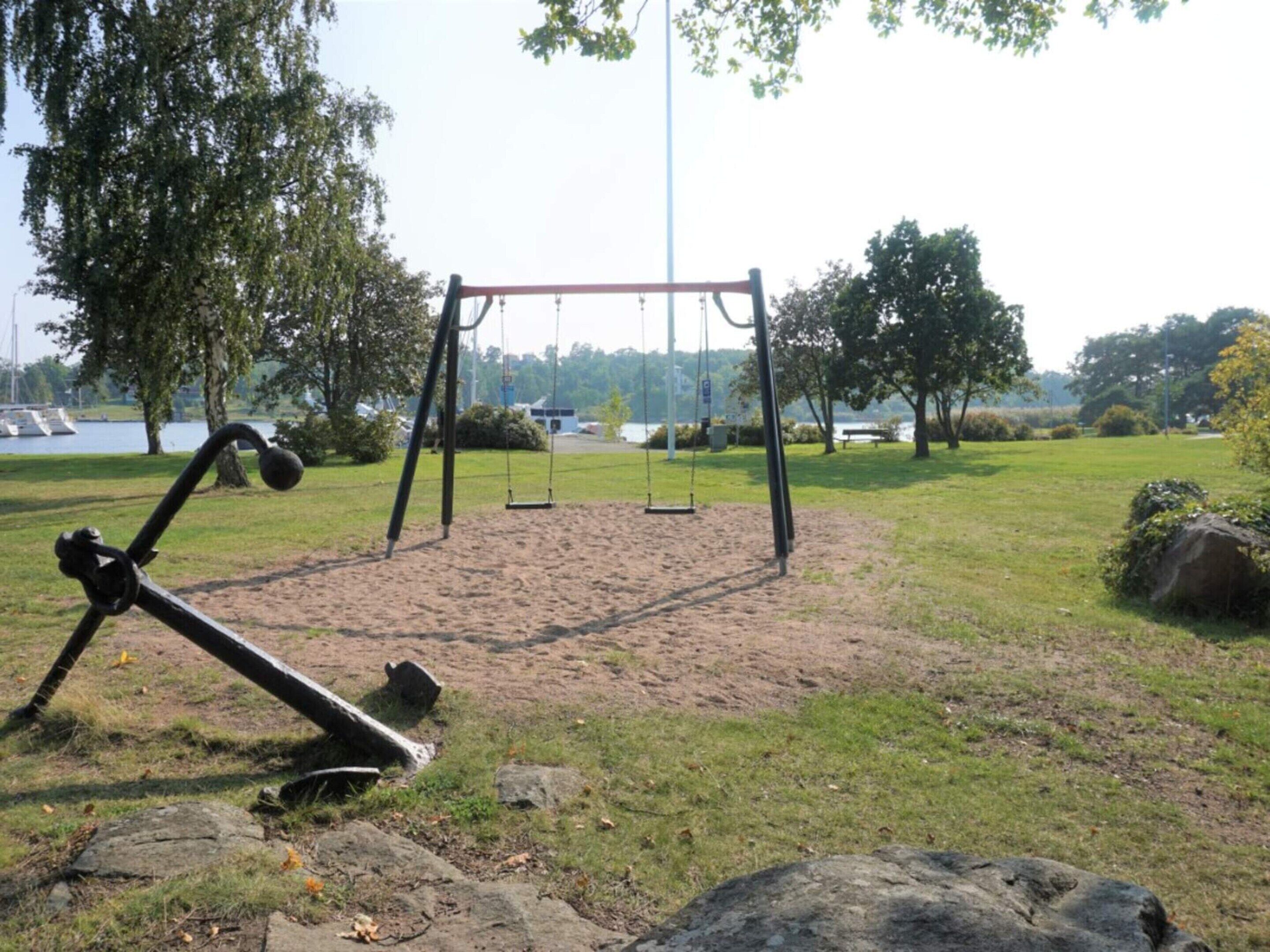 Um parque com baloiço e caixa de areia.