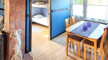 Um quarto com beliche, uma mesa de jantar e cadeiras, e uma estátua.