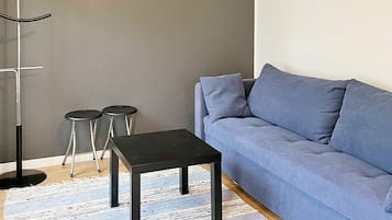 Uma sala de estar moderna com um sofá cinzento, duas mesinhas de cabeceira pretas e um abajur.