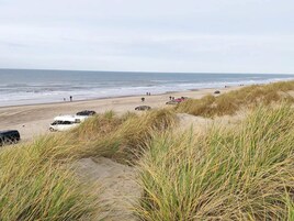 Uma praia com dunas e carros estacionados.