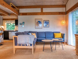Uma sala de estar moderna com um sofá, duas mesas redondas e vista para o exterior.