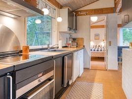 Uma cozinha moderna com forno embutido, lava-louças e uma grande janela com vista para o exterior.