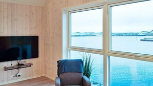 Quarto com uma grande janela que oferece vista para um corpo d'água e edifícios ao longe.