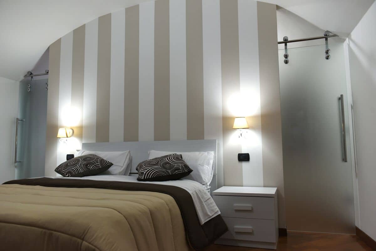 Quarto de hotel com cama, mesas de cabeceira e área de chuveiro.