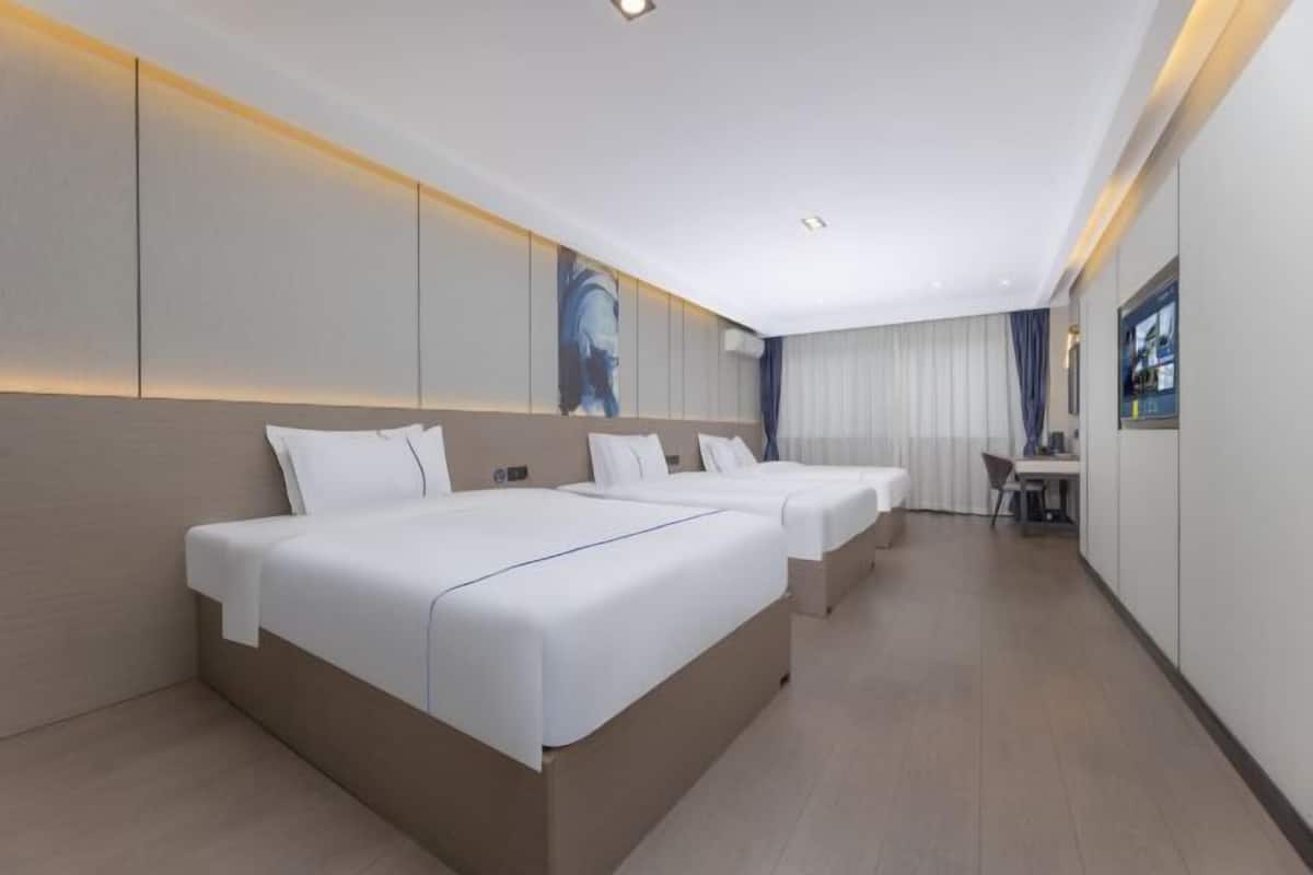 Quarto de hotel com duas camas, uma escrivaninha e uma cadeira.