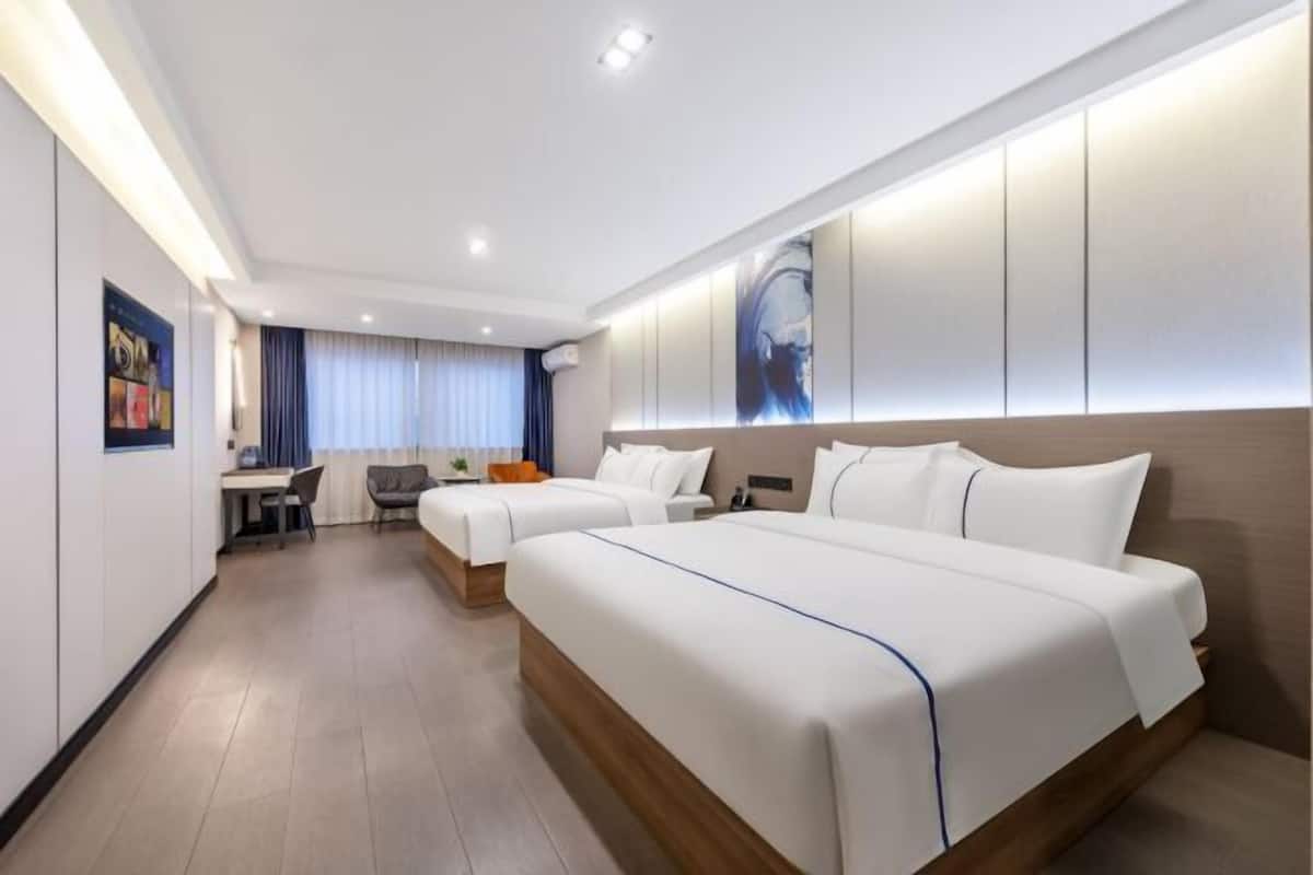 Quarto de hotel com duas camas, uma escrivaninha e uma cadeira.