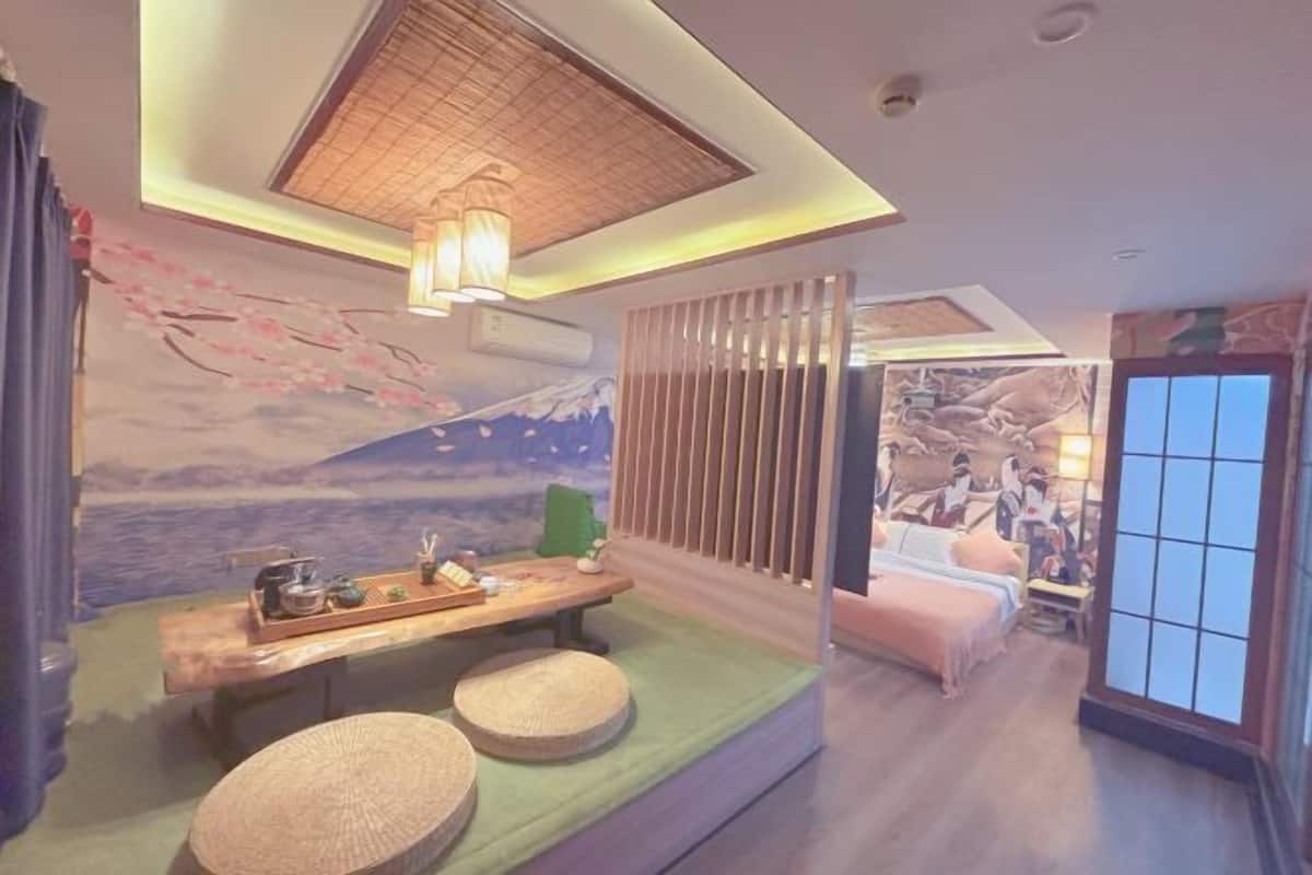 Quarto com um banco de madeira, uma cama e vista para um biombô tradicional japonês.