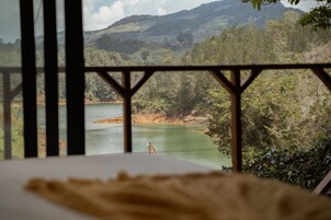 Quarto com vista para um rio e colinas.