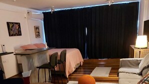 Um espaço de estar compacto com cozinha compacta, área de refeições e um espaço de descanso com sofá e apoio para os pés.