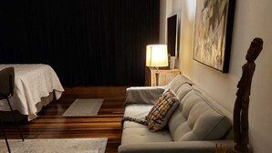 Uma sala de estar moderna com um sofá, uma mesa redonda, um abajur e uma escultura decorativa.