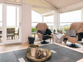 Um interior moderno com duas poltronas confortáveis, uma mesa pequena e vista para o exterior.