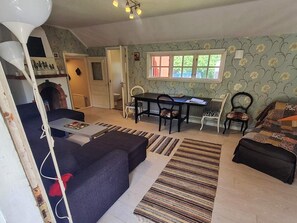 Uma sala de estar com sofá, mesa de jantar com cadeiras, lareira e janela com vista para o exterior.