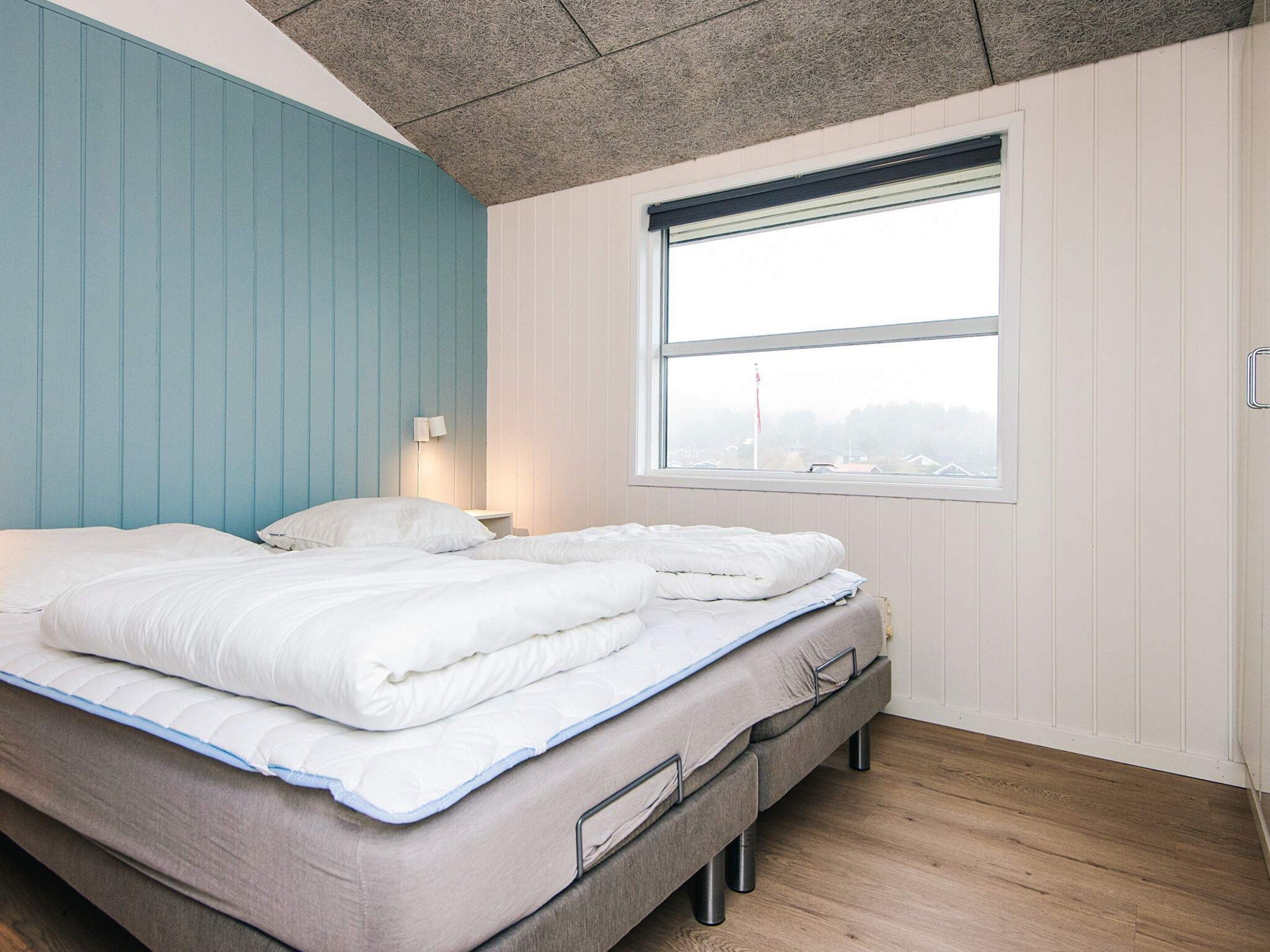 Quarto com cama, janela e mesa de cabeceira.